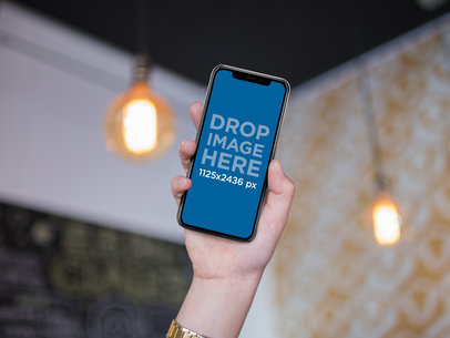 Placeit - iPhone Being Held By A Womans Hand Inside A Room With Hanging ...