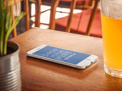 Placeit - Mockup of an iPhone 6 on Wooden Table Next to a Beer