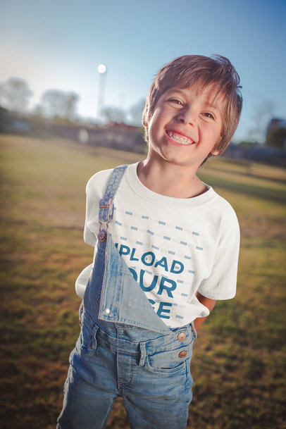 Placeit - Transparent Smiling Kid Wearing a T-Shirt Mockup at a Park