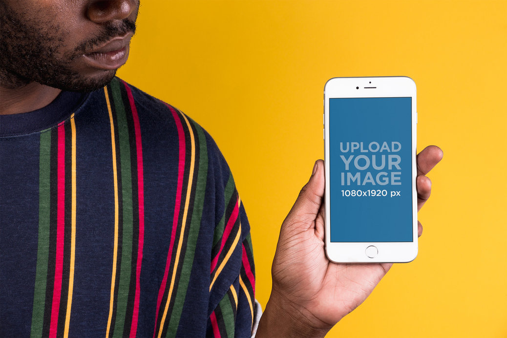 Placeit - Mockup of a Man with a Holding an iPhone Against a Yellow Wall